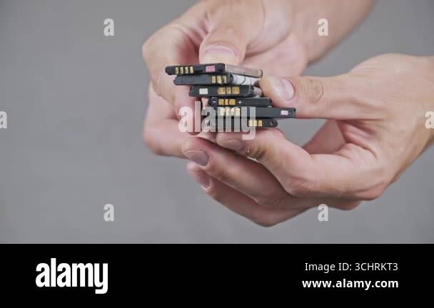 Close-up of hands holding a stack of old, used lithium-ion batteries ...