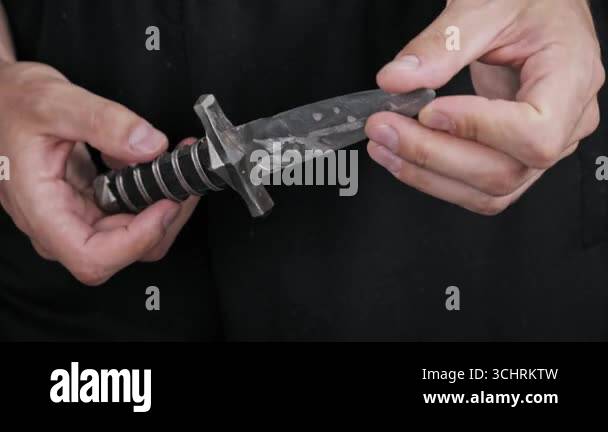 Close-up of a person carefully examining the sharp edge and ornate hilt ...