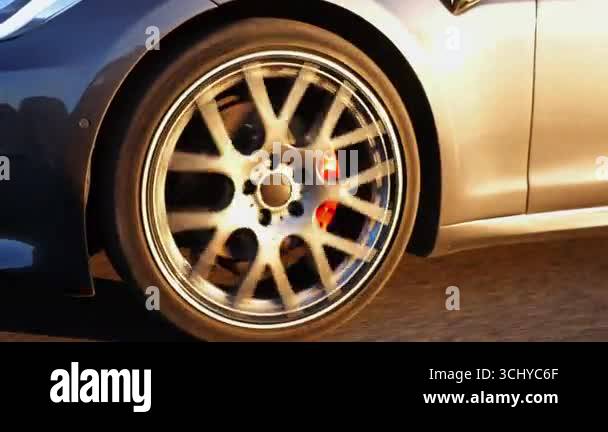 Wheel of modern electrical automobile driving at urban road on sunny ...