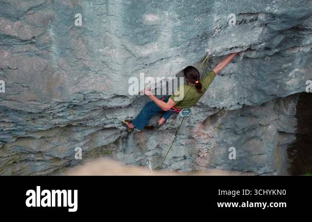 Strong rock climber lead climbing on overhanging rock face, rock ...