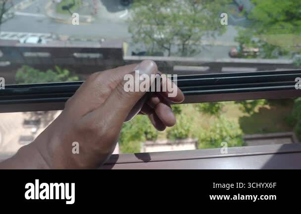 human hand gripping a window frame with an outdoor urban view Stock ...