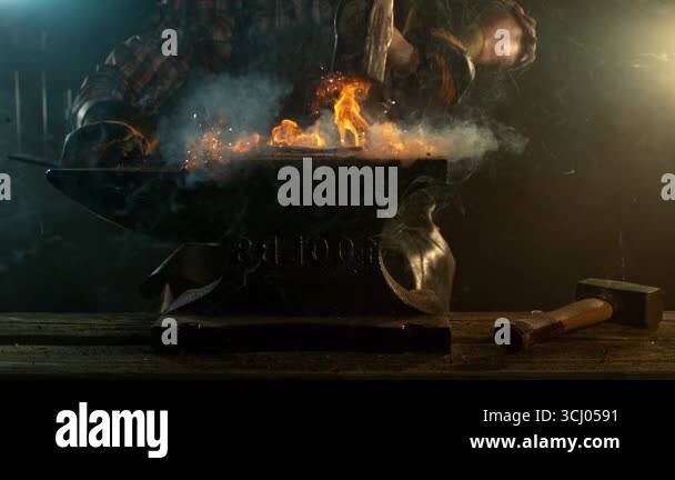 Close-up of blacksmith forging glowing hot iron on anvil with flying ...