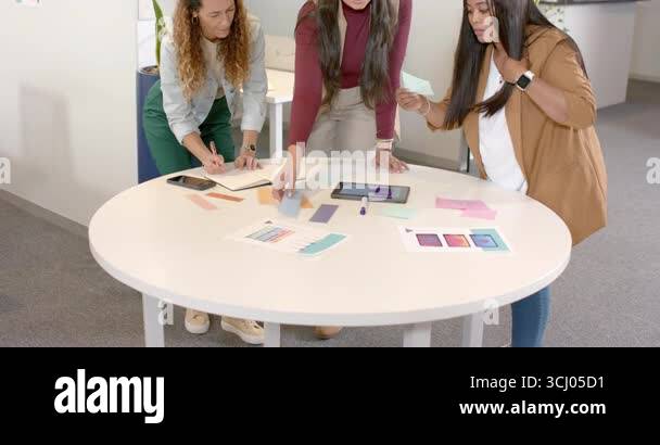 Spotting color swatches, diverse female colleagues collaborating on ...
