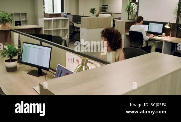 Diverse coworkers reviewing spreadsheets on dual monitors and sharing ...