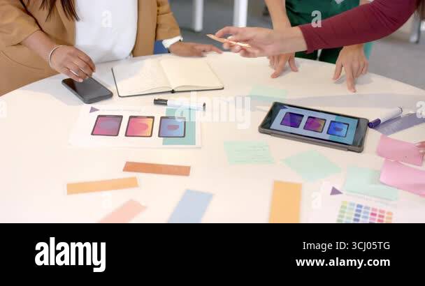 Diverse female team reviewing design by pointing at tablet and labeling ...