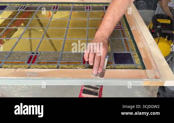 Craftsman restoring a vintage stained glass window, applying wood ...
