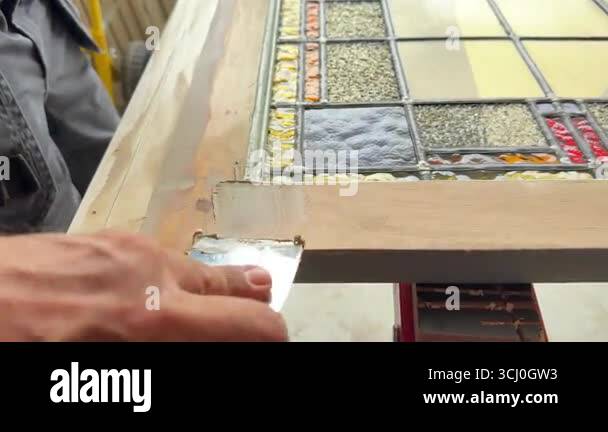 Craftsman restoring a vintage stained glass window, applying wood ...