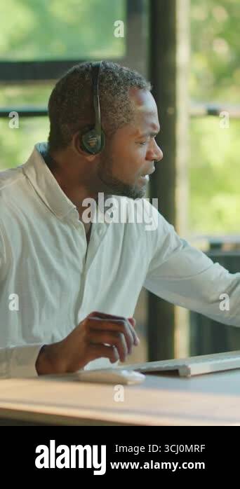 A skilled professional man, wearing a headset, is fully engaged in his ...