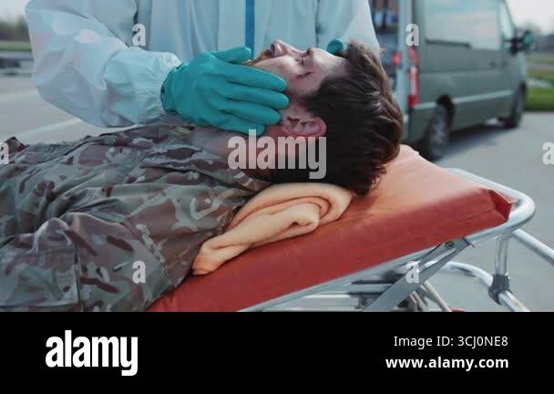 Doctor examining shrapnel wound on face of soldier wounded by artillery ...