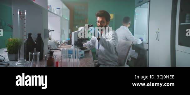 Slow motion young man scientist with glasses and protective gloves ...