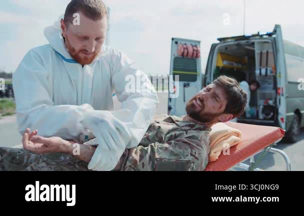 Experienced doctor examining military man in uniform lying on medical ...