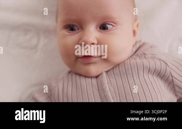 Charming funny face of little newborn baby smiling, lying at the back ...