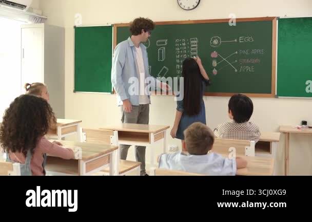 Young asian girl writing math formula at blackboard while standing at ...
