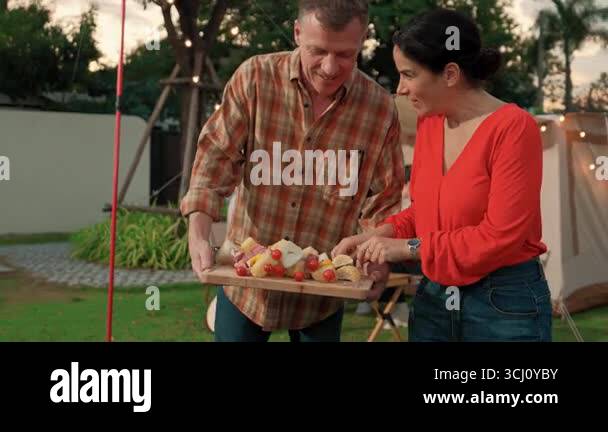 Family all together camp in garden, Old couple cooking BBQ, having a meal. Senior use outdoor ...