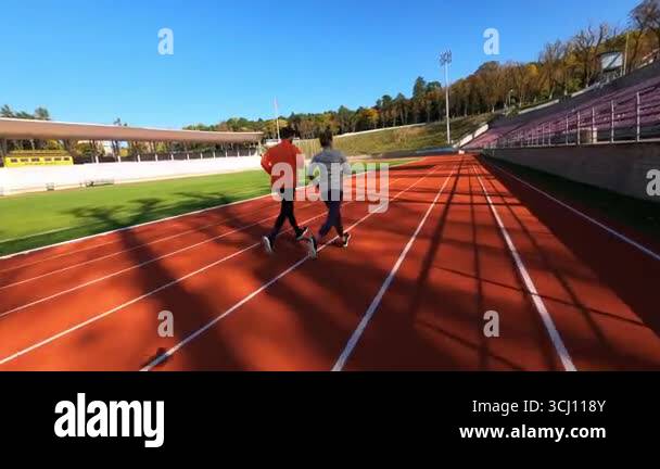 Sportive couple of motivated runners performing warming up jogging ...
