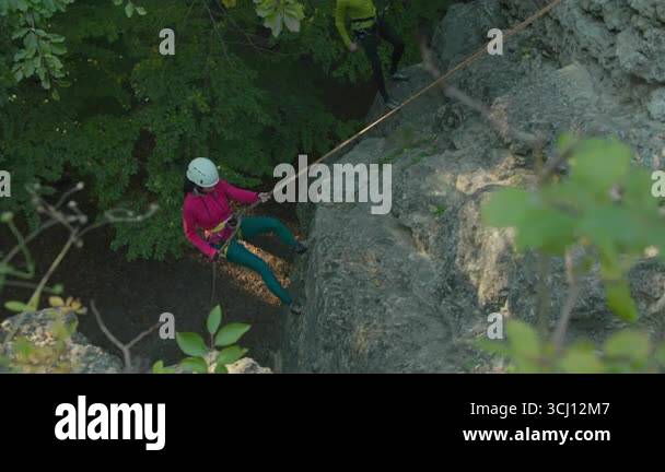 Aerial shot young woman in helmet protection with safety ropes climbing ...