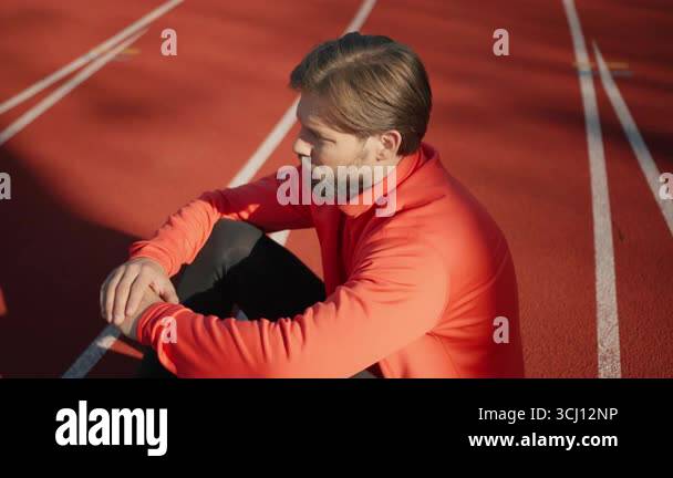 Young caucasian male athlete with beard sitting on sports ground ...