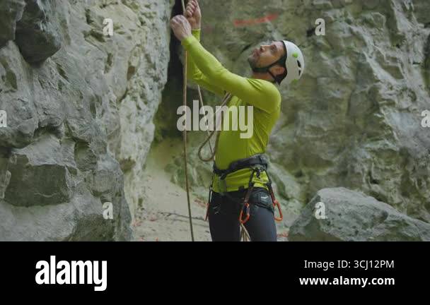 Caucasian handsome bearded climber adjusting climbing equipment long ...