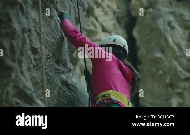 Young beautiful fit sportswoman climbing on the rock, gripping holds ...