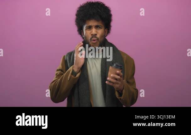 Man holding coffee cup with african heritage stands against pink ...