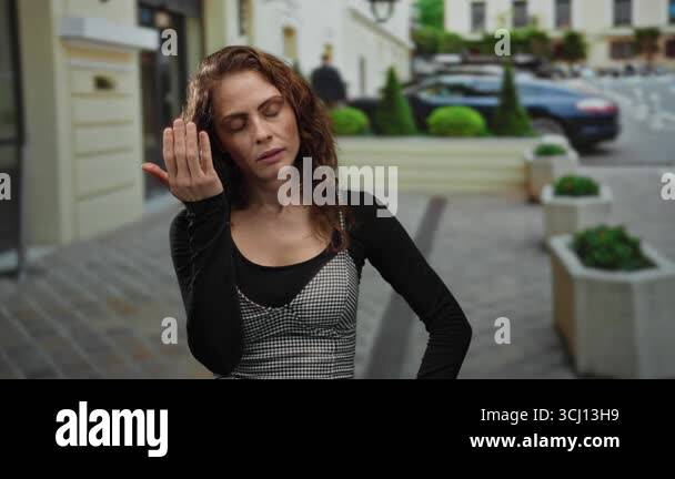 Woman with curly hair on city street appearing stressed with eyes ...