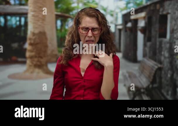 Woman crying in city street outdoor wearing red glasses and shirt with ...