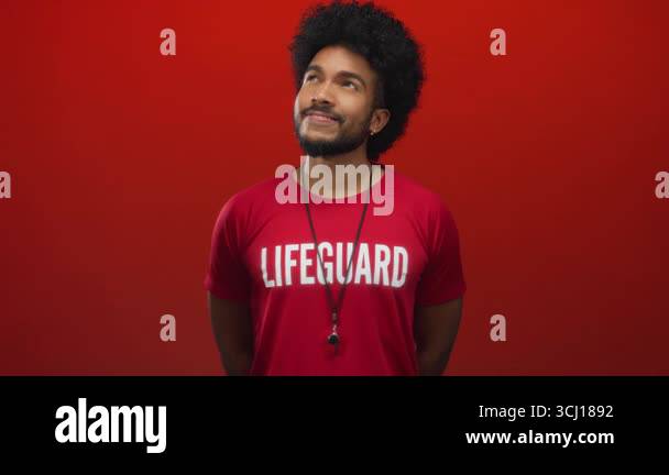 Smiling lifeguard man in red shirt with whistle isolated against ...