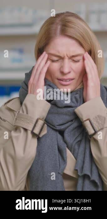 Sick caucasian woman in coat wearing scarf having terrible headache ...