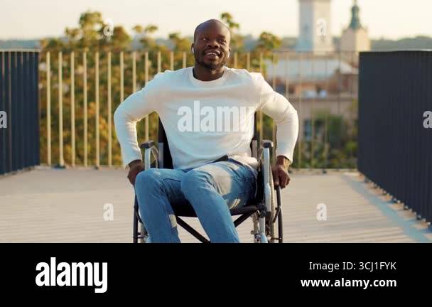 Close up young man use headphones speaking phone on a wheelchair in a ...