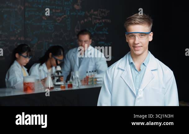 Smart student looking at camera while diverse group doing experiment ...