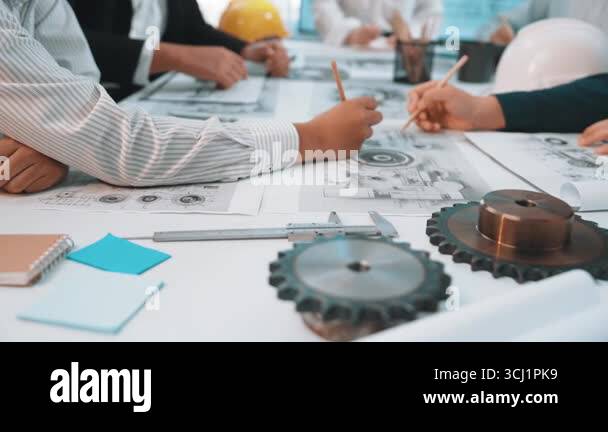Engineers gather around a table, discussing and reviewing technical ...