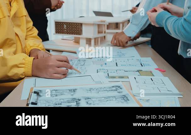 Engineers and architects collaborate around a table filled with ...