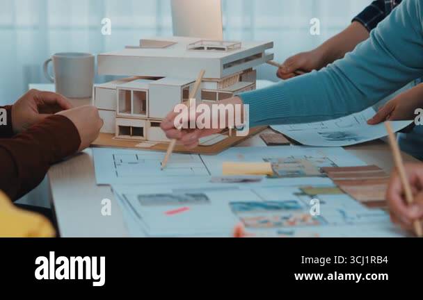 A collaborative team engages in a meaningful discussion about an architectural model and ...