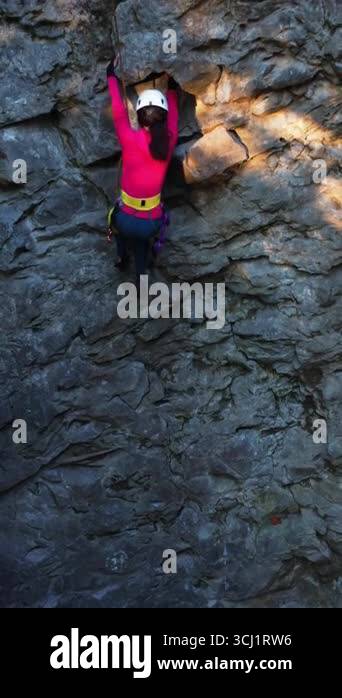 Aerial footage of young brunette sportswoman climbing on mountain stone ...