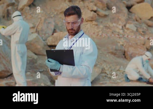 Serious ecology expert man stand writing in protection wear working on ...