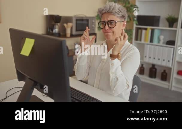 Woman pumps raised fists at large widescreen computer monitor in bright ...