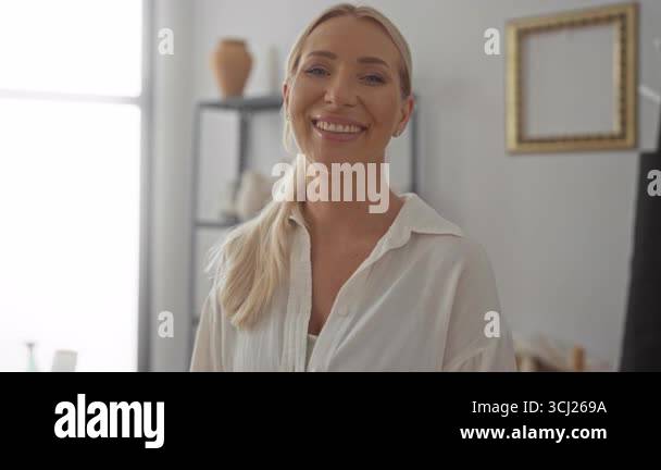 Woman smiles gently in studio under soft overhead lighting, posing with ...