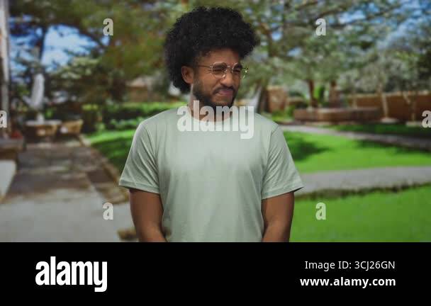 African american man with glasses making a displeased face in a green ...