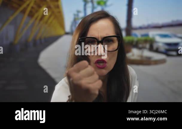 Woman shouting angrily on street with clenched fist in vibrant urban ...