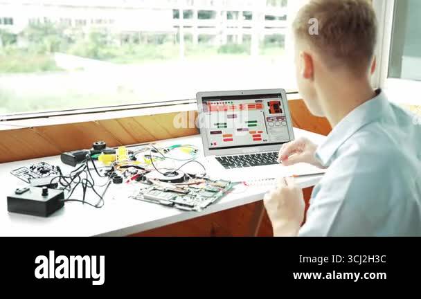 Caucasian student looking at laptop screen while coding engineering prompt or programming system ...