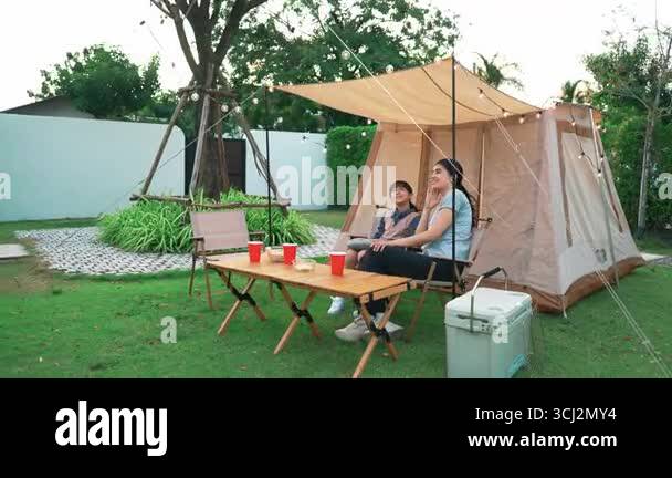 Family all together sit at camp in garden then having a meal. Parent use outdoor camping ...