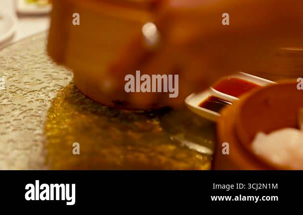 A hand serves dim sum from bamboo steamers in a warmly lit Chinese ...