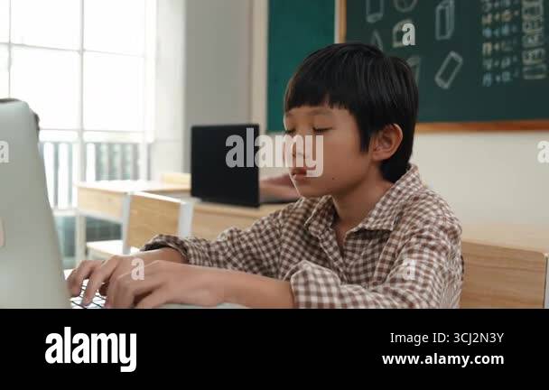 Asian boy working on his laptop while learning about coding engineering prompt at STEM ...