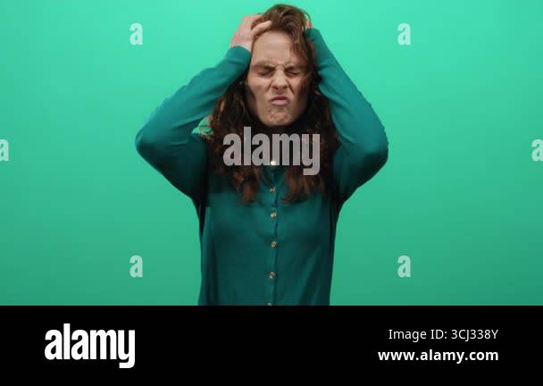 Woman expressing frustration with hands on head against isolated green ...