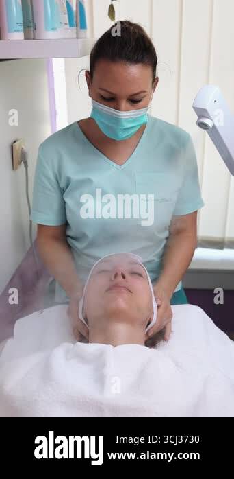 Young woman receiving beauty treatment with thermal ozone facial steamer. Professional ...