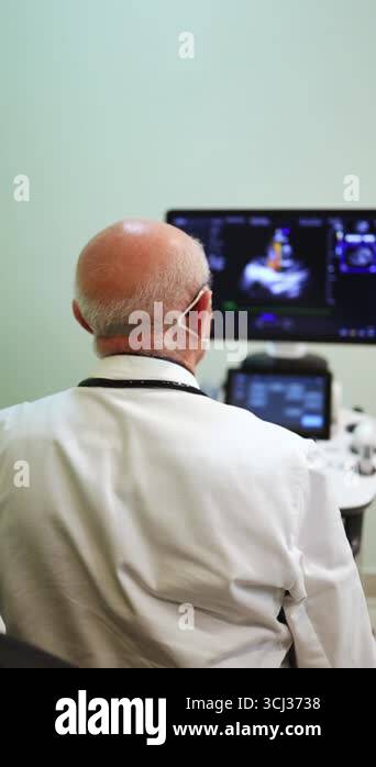 Senior cardiologist wearing a white coat and face mask working on a ...