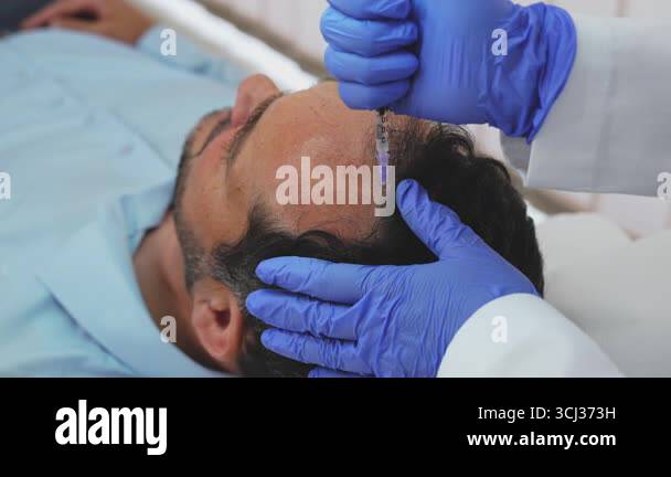 Doctor wearing blue gloves is injecting medicine into a patient's head ...