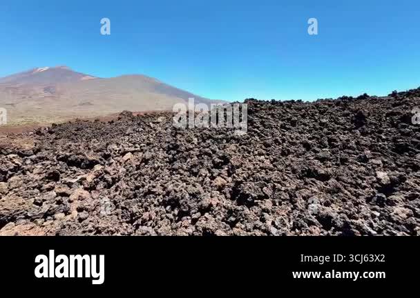 A stunning view of barren lava fields against a majestic volcanic mountain backdrop under a ...