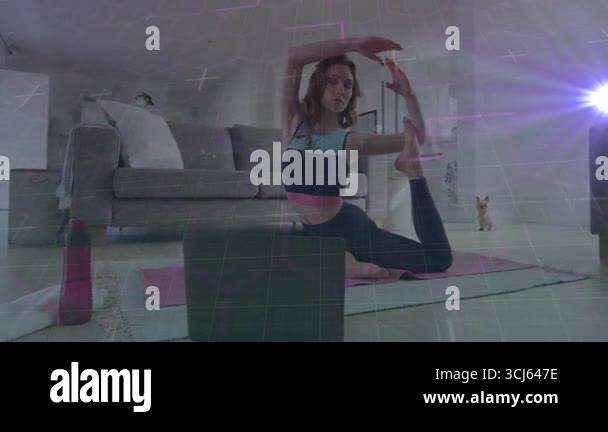 Woman kneeling on mat entering mermaid pose following laptop fitness app cues flickering ...