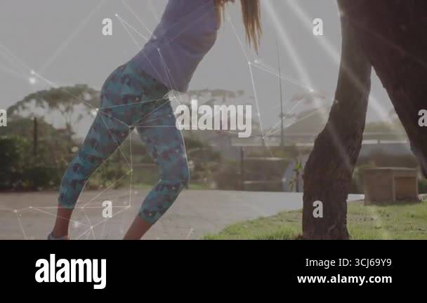 Woman athlete stepping back on park path pressing against tree and ...